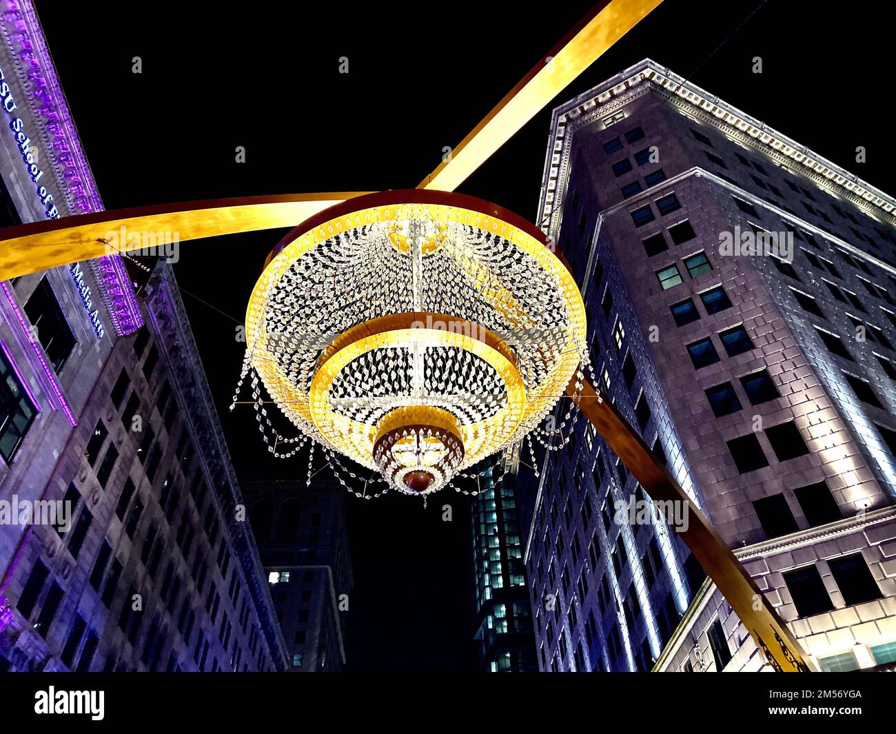 A low angle shot of a lit chandelier on a street with buildings in the ...
