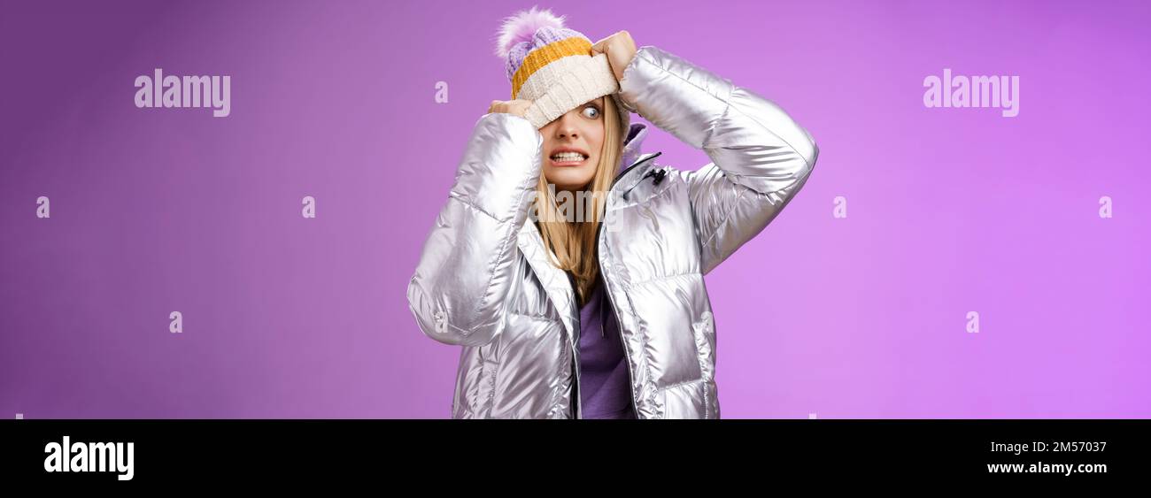 Awkward embarrassed cute blond girl worried pulling hat face hiding ...