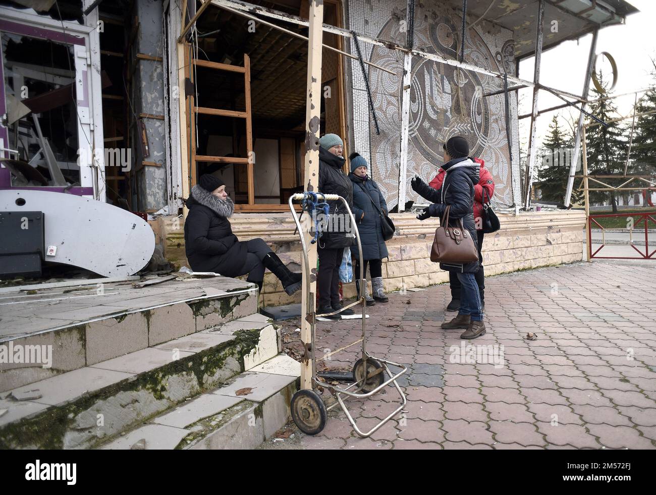 IZIUM, UKRAINE - DECEMBER 25, 2022 - People stay by a building ...