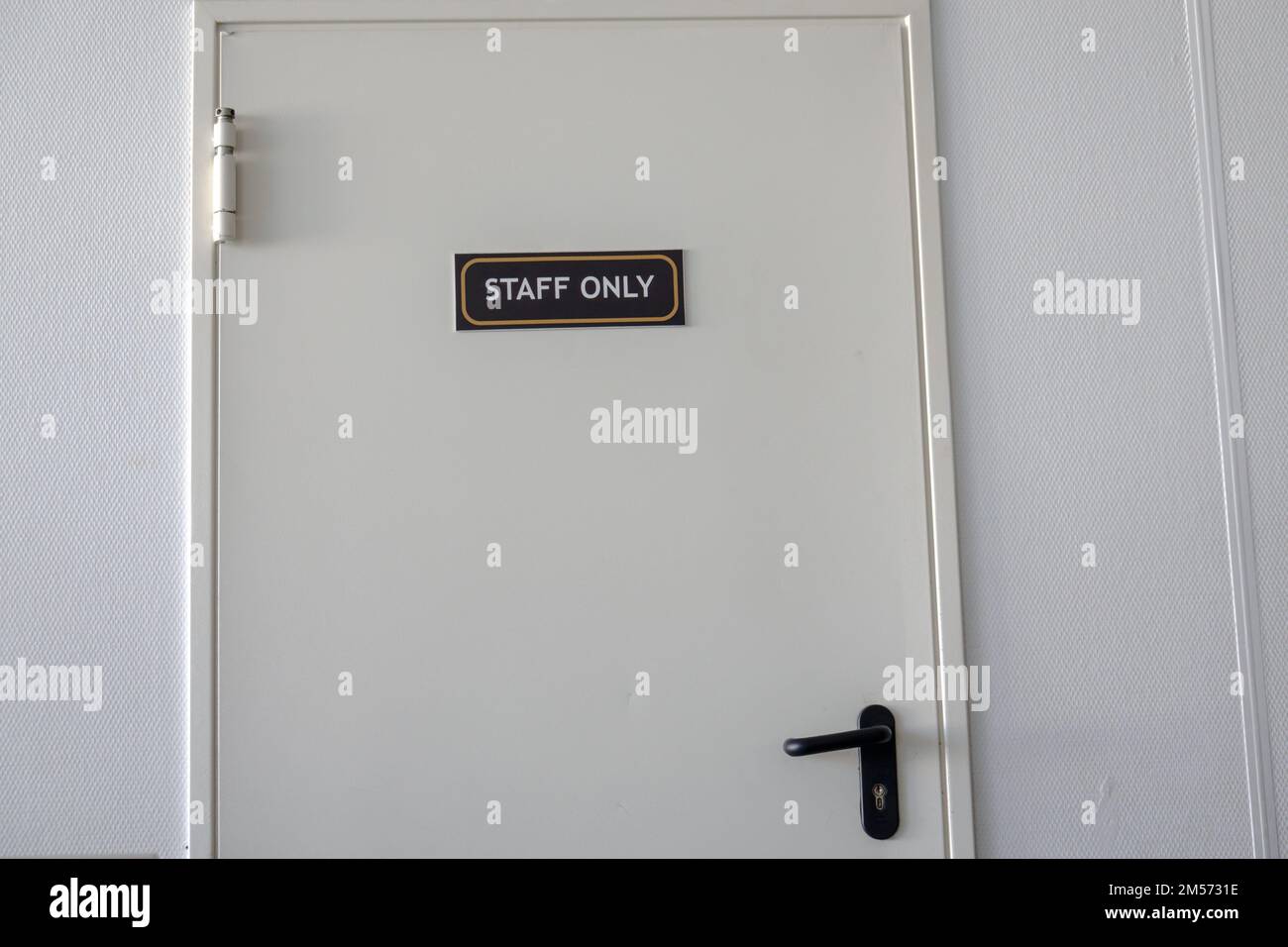 Low angle of closed door with Staff Only signboard installed on white ...
