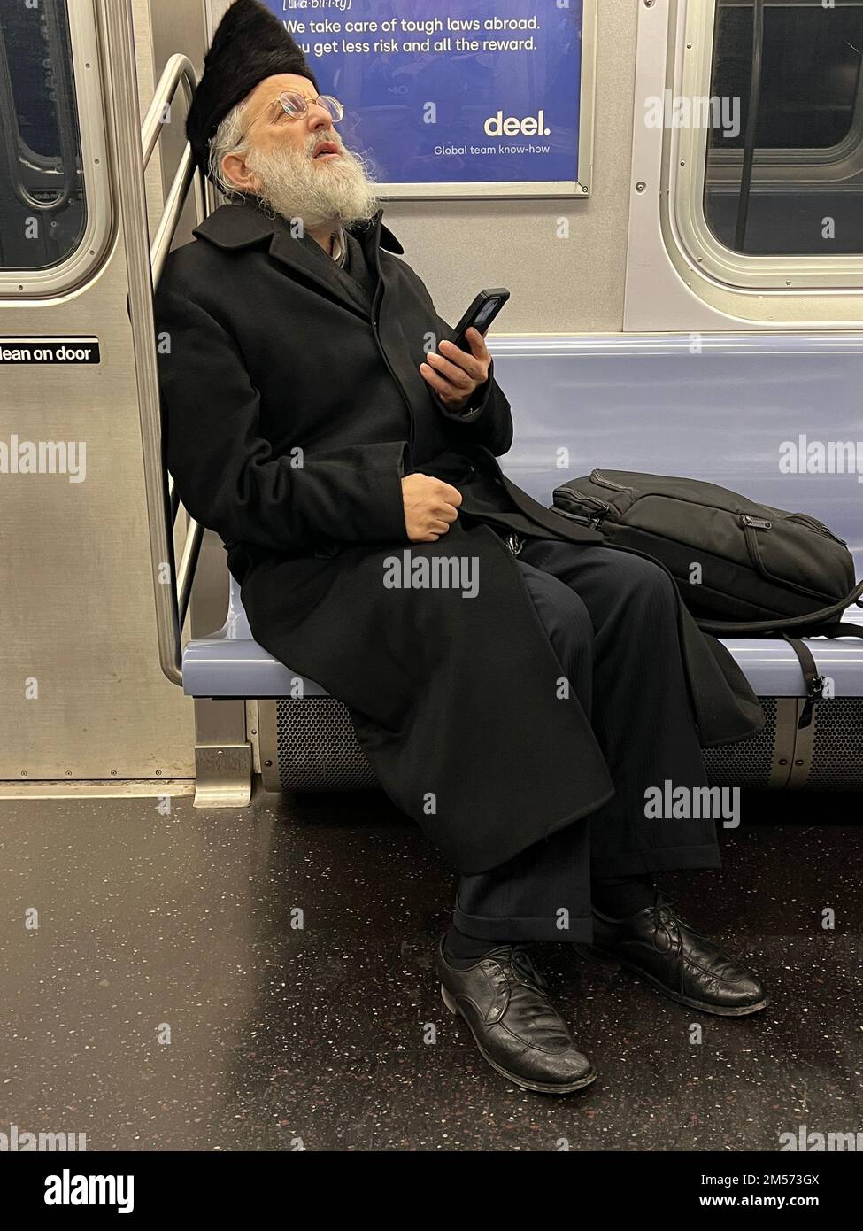 Orthodox Jewish man in prayer with his smartphone as he rides a subway ...