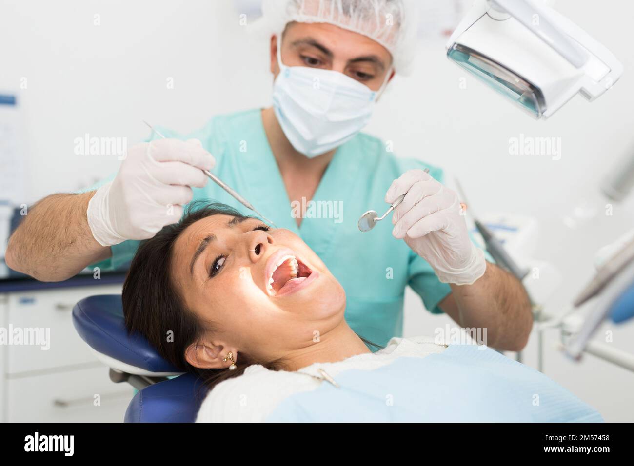 Dentist man examining a latin female patient teeth Stock Photo - Alamy
