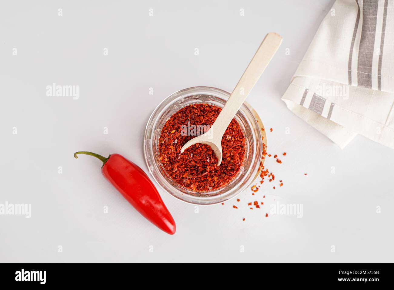 Glass with chipotle chili flakes on light background Stock Photo - Alamy