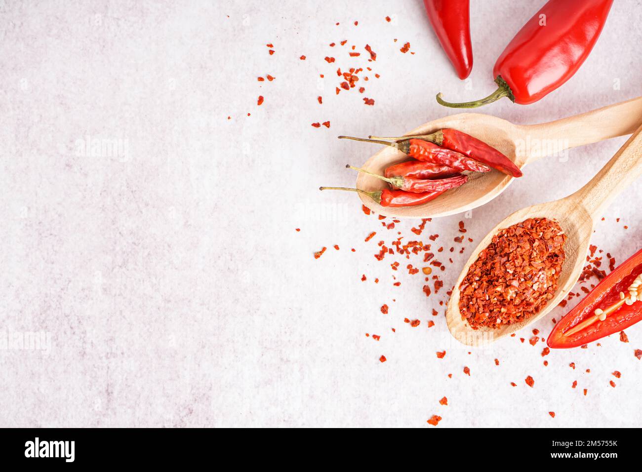 Spoons with chipotle chili flakes and dried jalapeno peppers on light ...