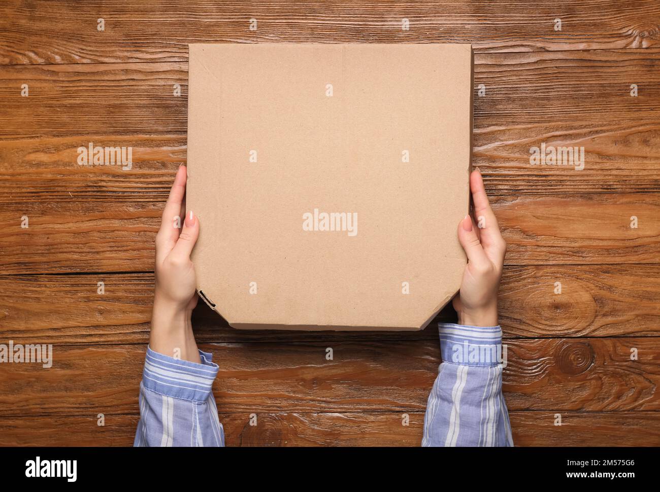 Female hands with pizza box on wooden background Stock Photo - Alamy