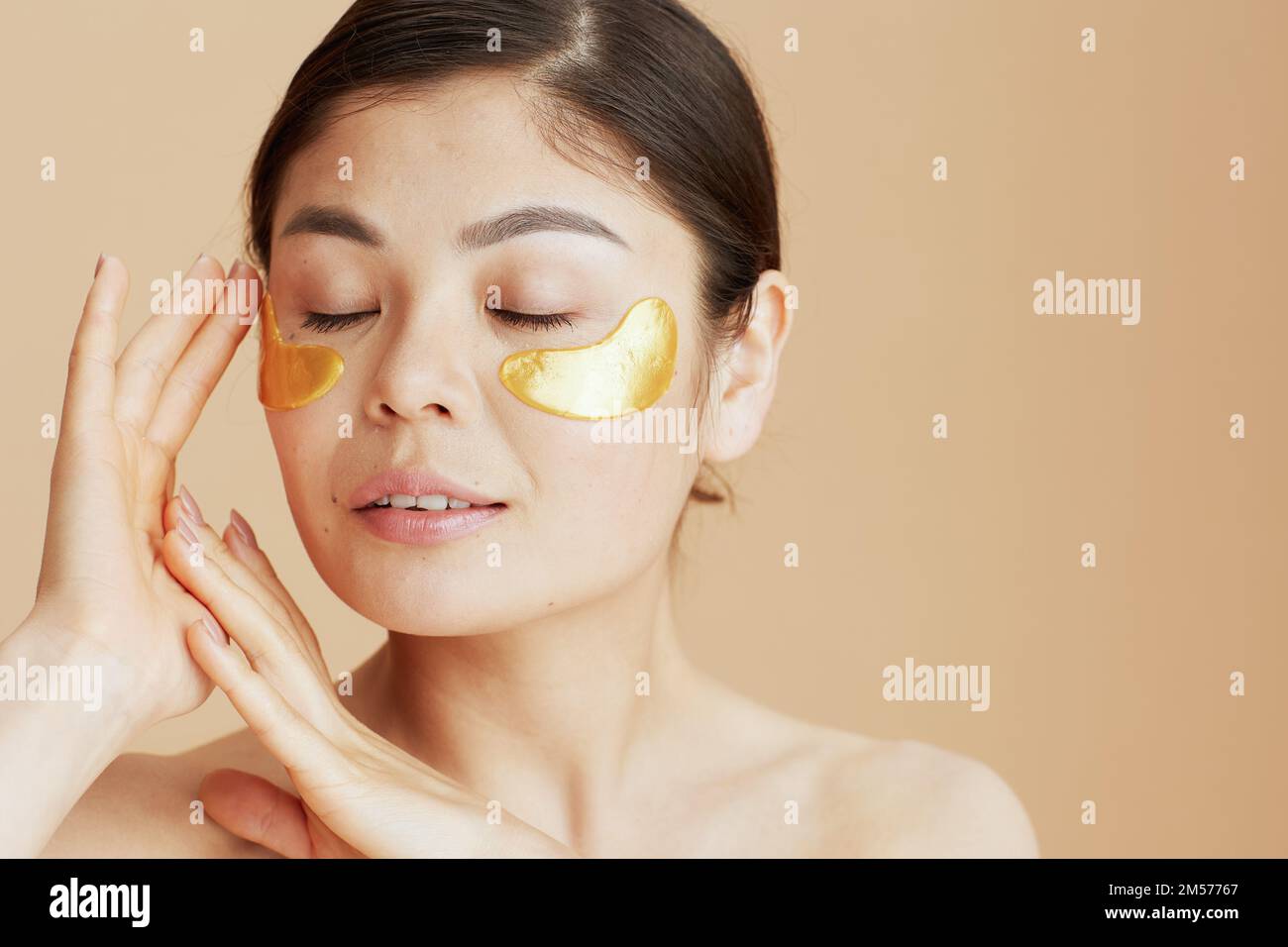relaxed modern asian woman with eye patches isolated on beige ...