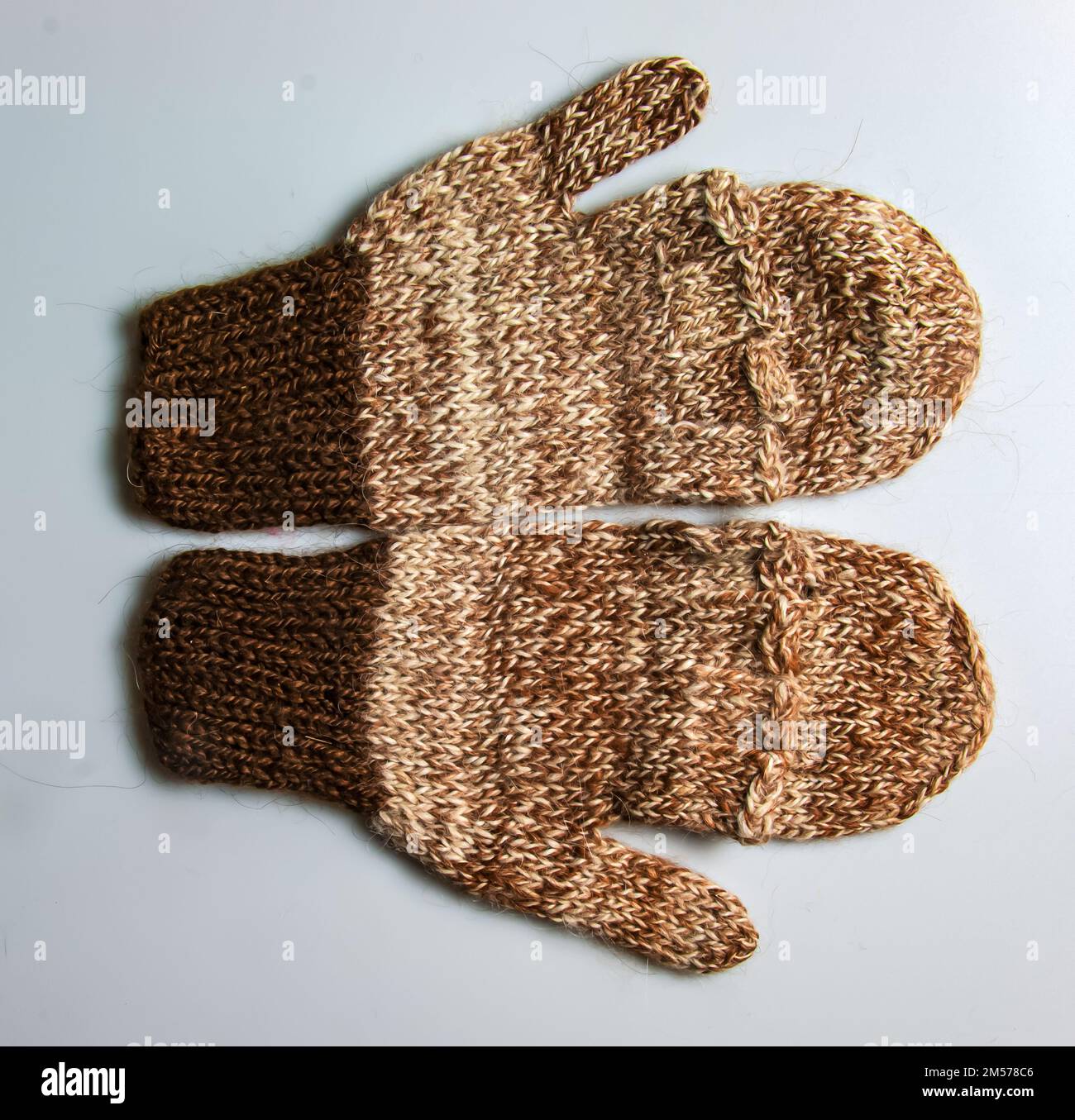 Handmade brown-beige mittens from Argentinean merino wool on a white ...