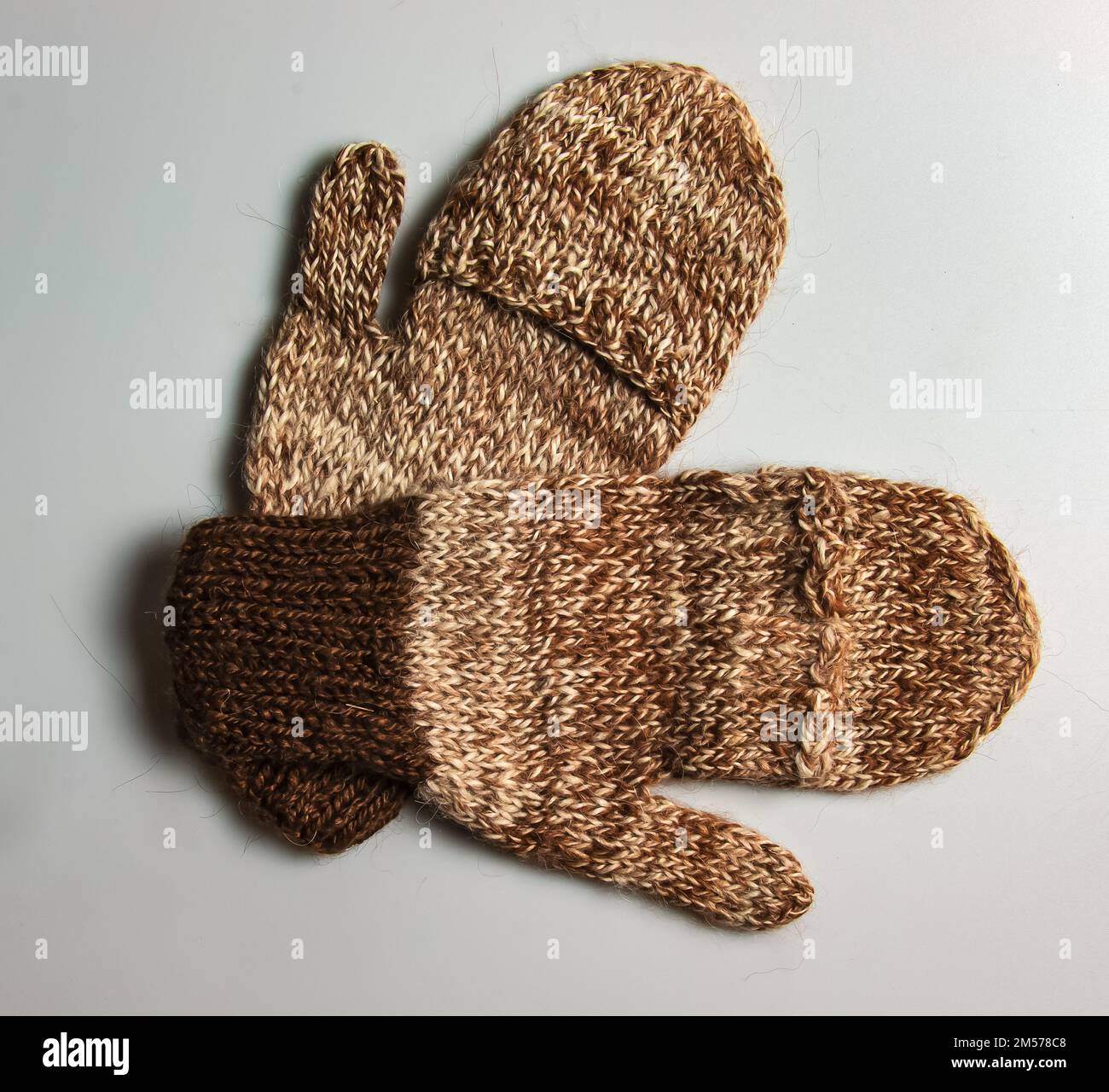 Handmade brown-beige mittens from Argentinean merino wool on a white ...