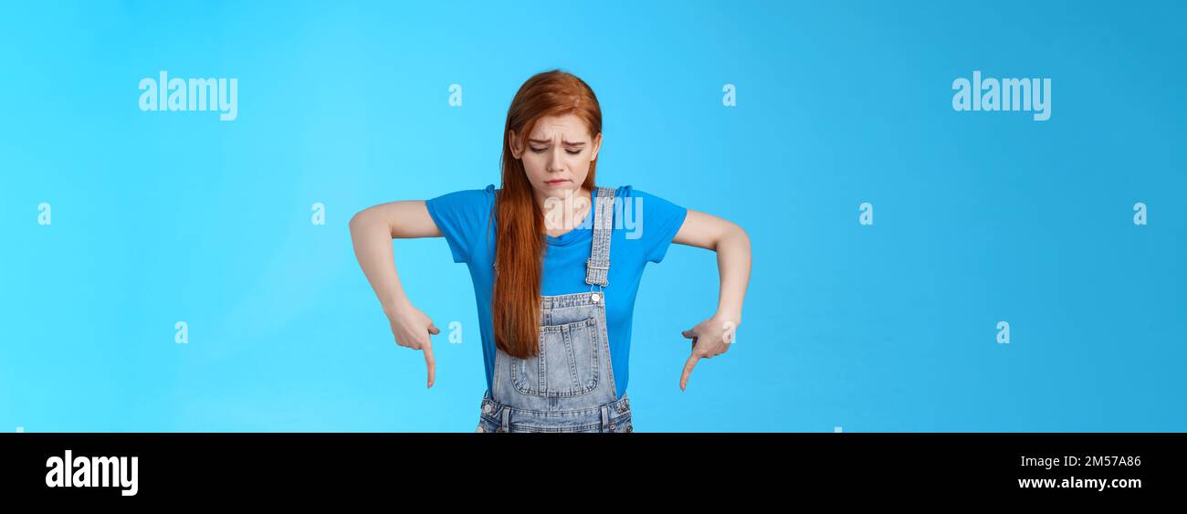 Moody upset cute redhead woman feel uneasy, frowning look pointing up ...