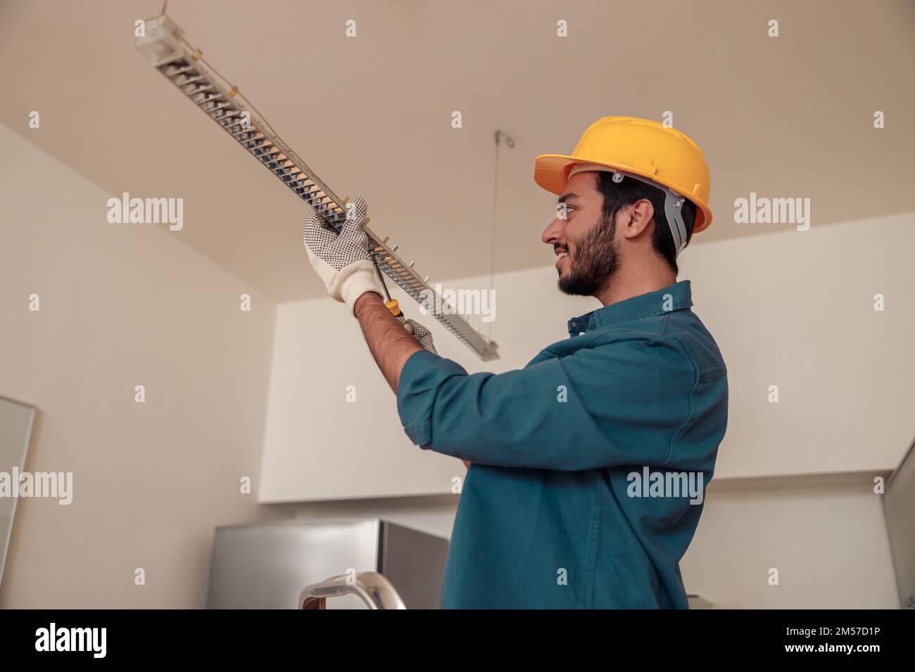 Smiling Professional electrician worker in uniform is installing ...