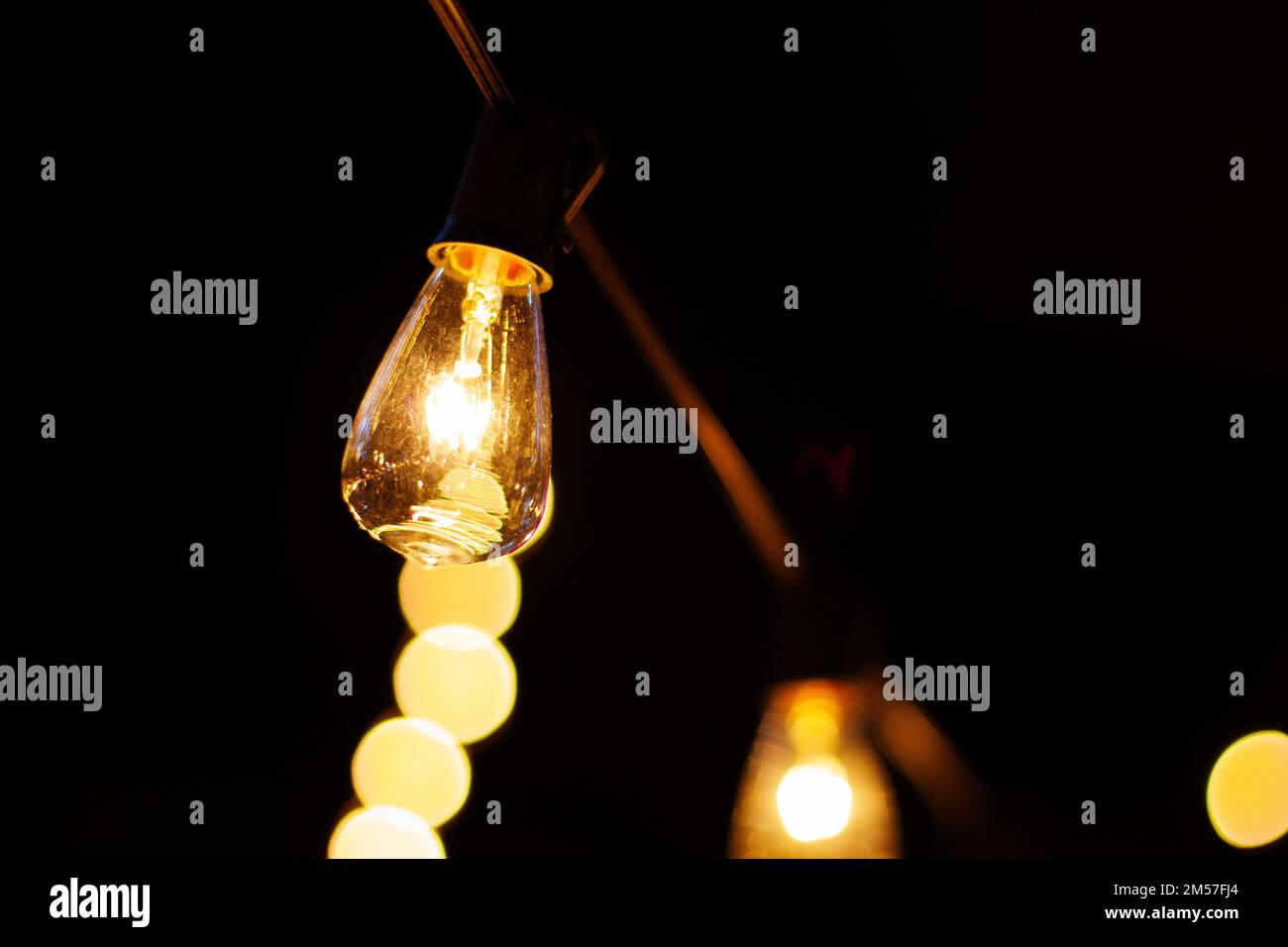 hanging lit light bulb, black background Stock Photo - Alamy