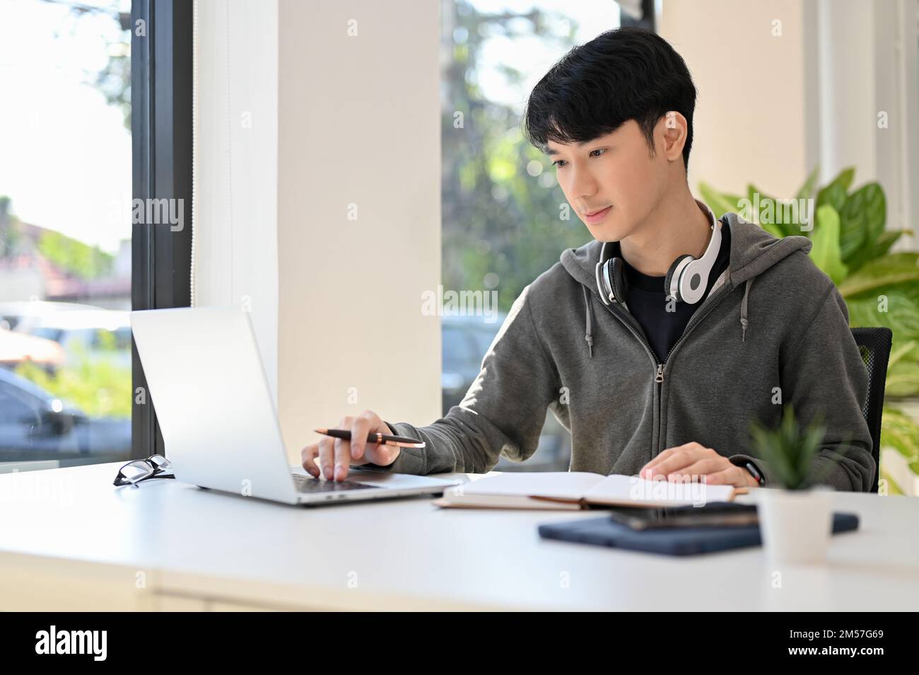 Smart young Asian male college student doing his school homework ...