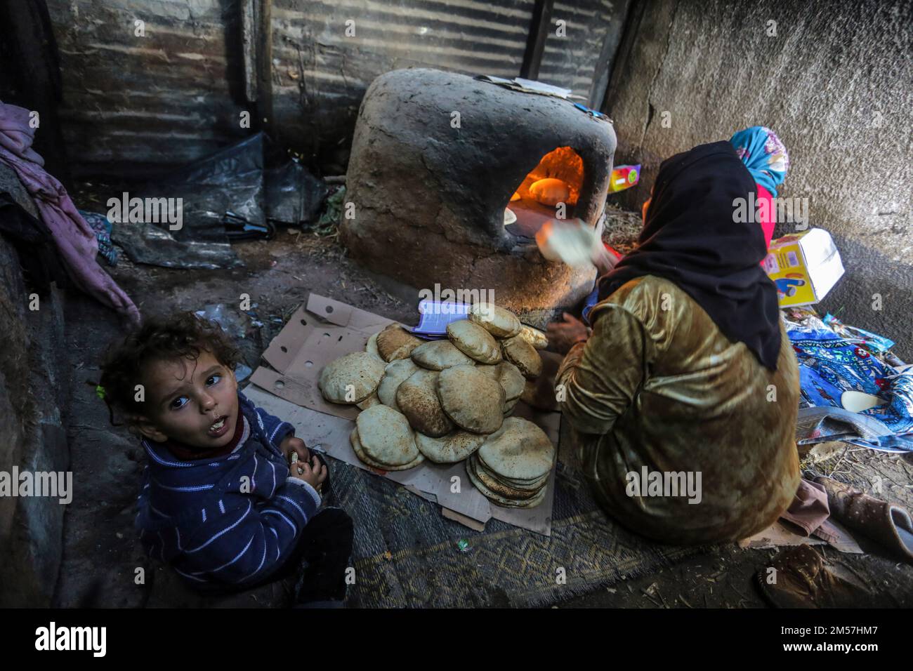Palestinian refugees bake taboon bread in their temporary home during ...