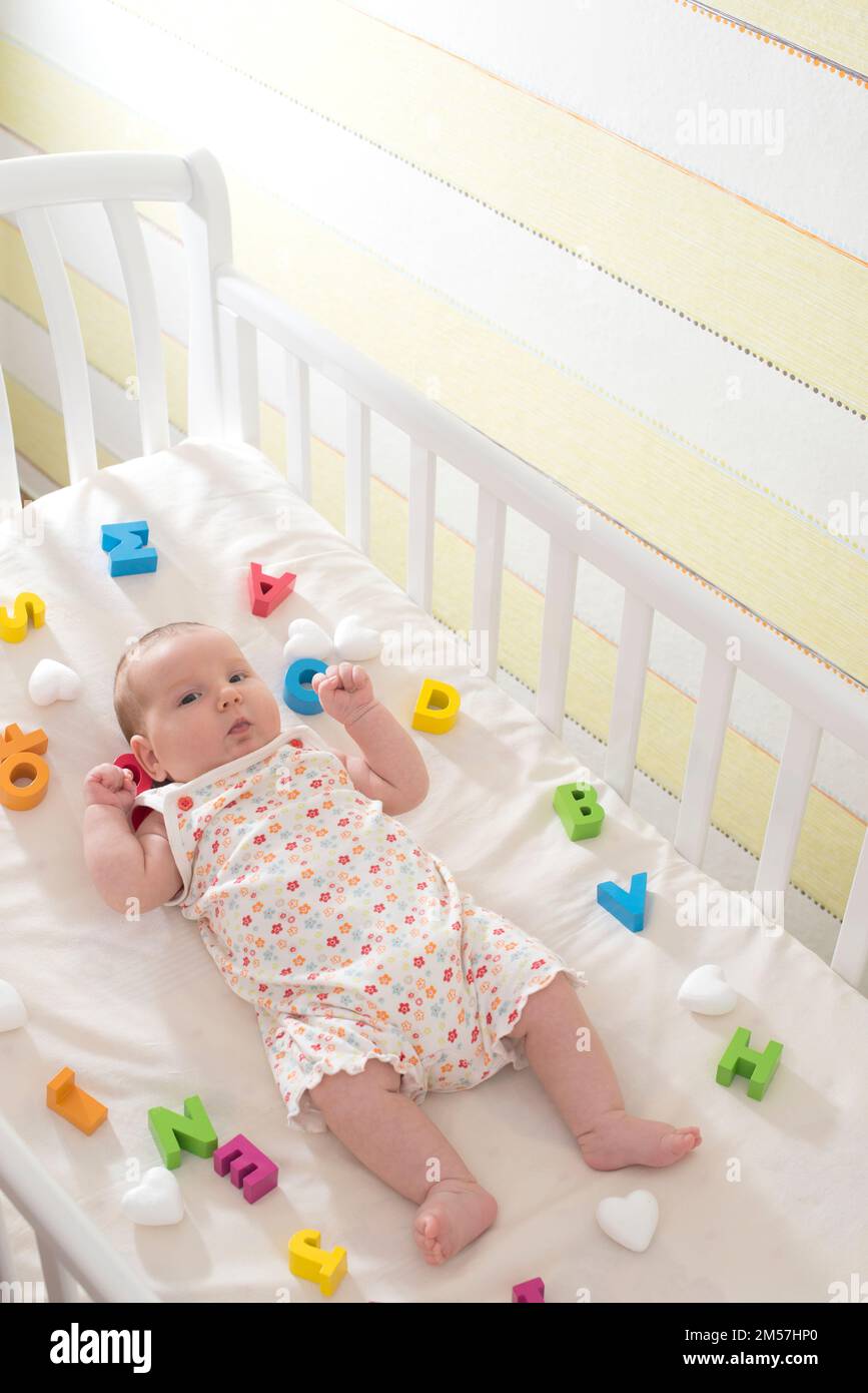 Baby girl in a baby bed. Wooden letters aroud the baby Stock Photo - Alamy