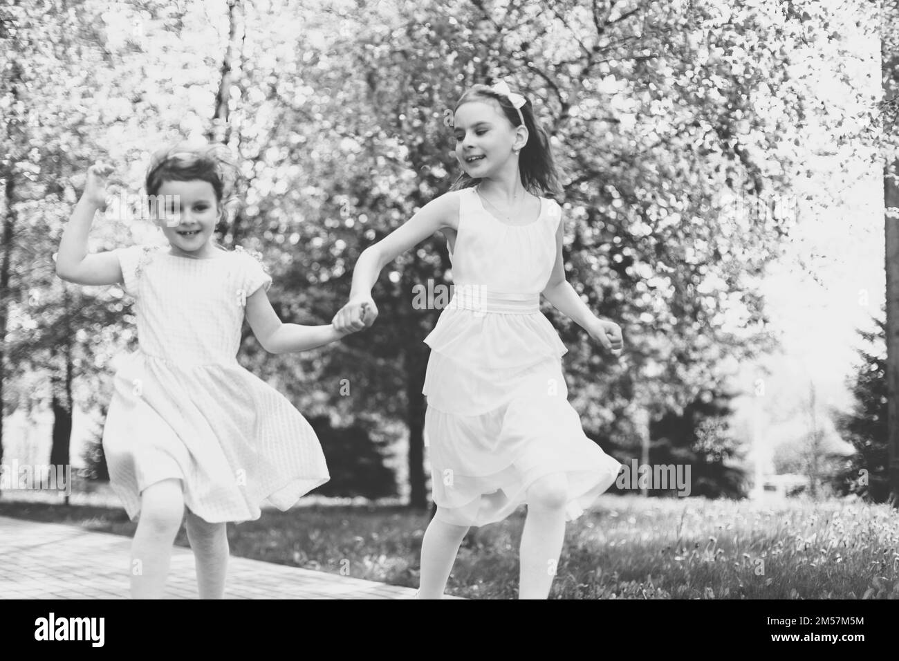 two little girls are running merrily along the path of the city. black ...