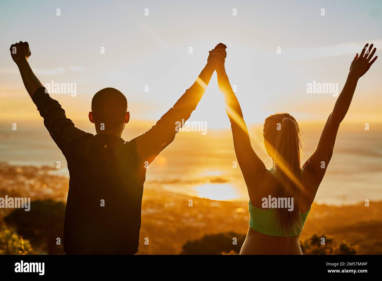 We did it. Rearview shot of two young people standing with their arms ...