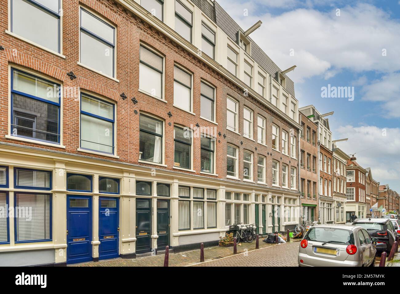 a city street with cars parked on the side and people walking down the ...