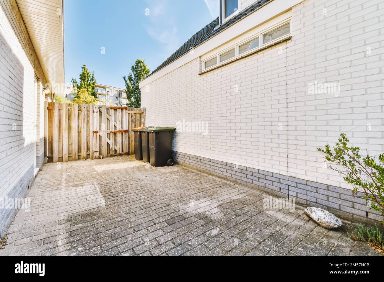 an empty back yard with white brick walls and green trees in the area ...