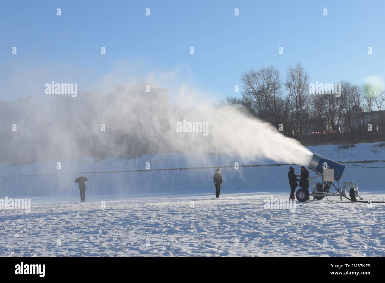 Workers use a snow gun to make artificial snow for the coming ice and ...