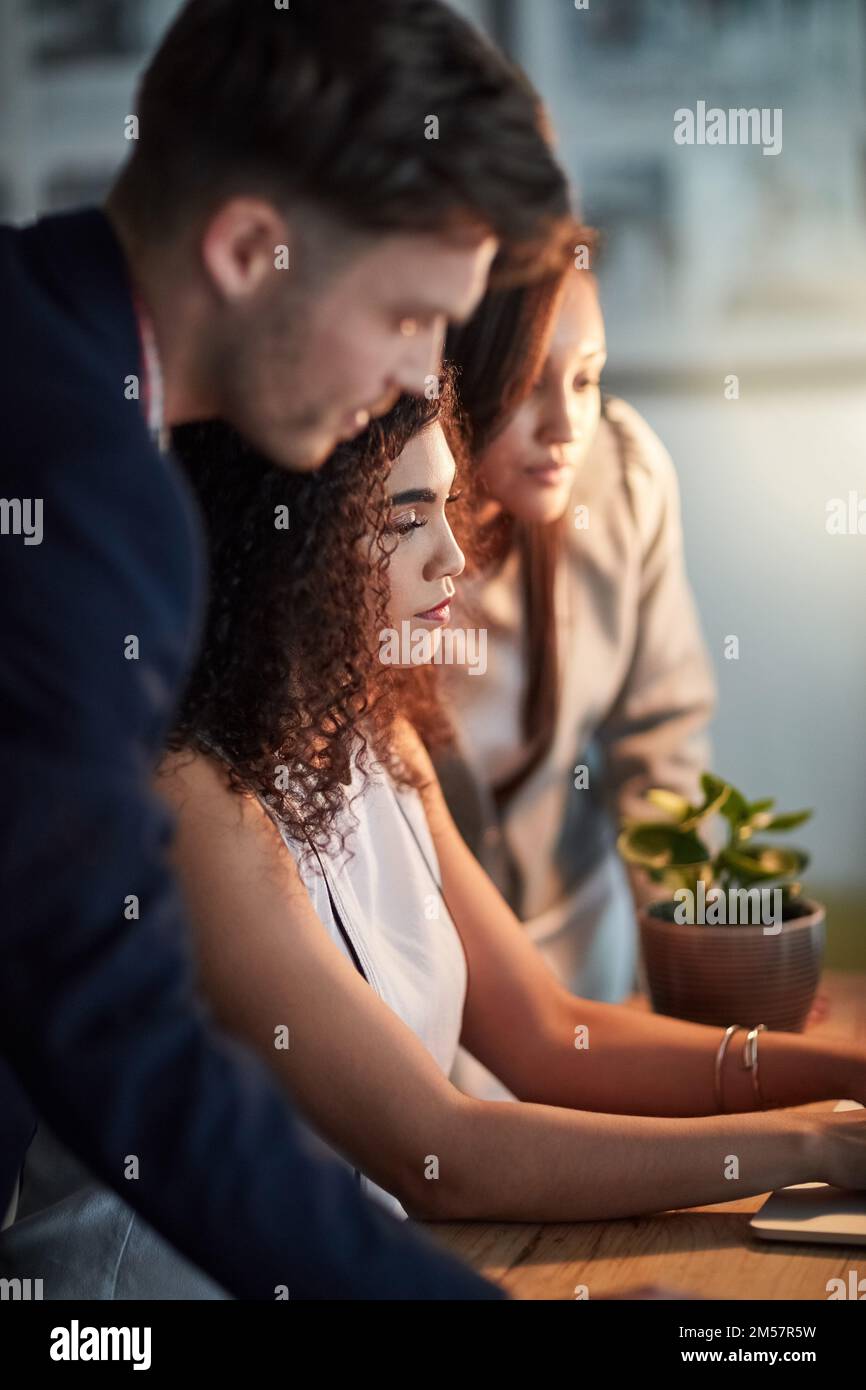 All hands on deck. three colleagues working together on a computer in ...