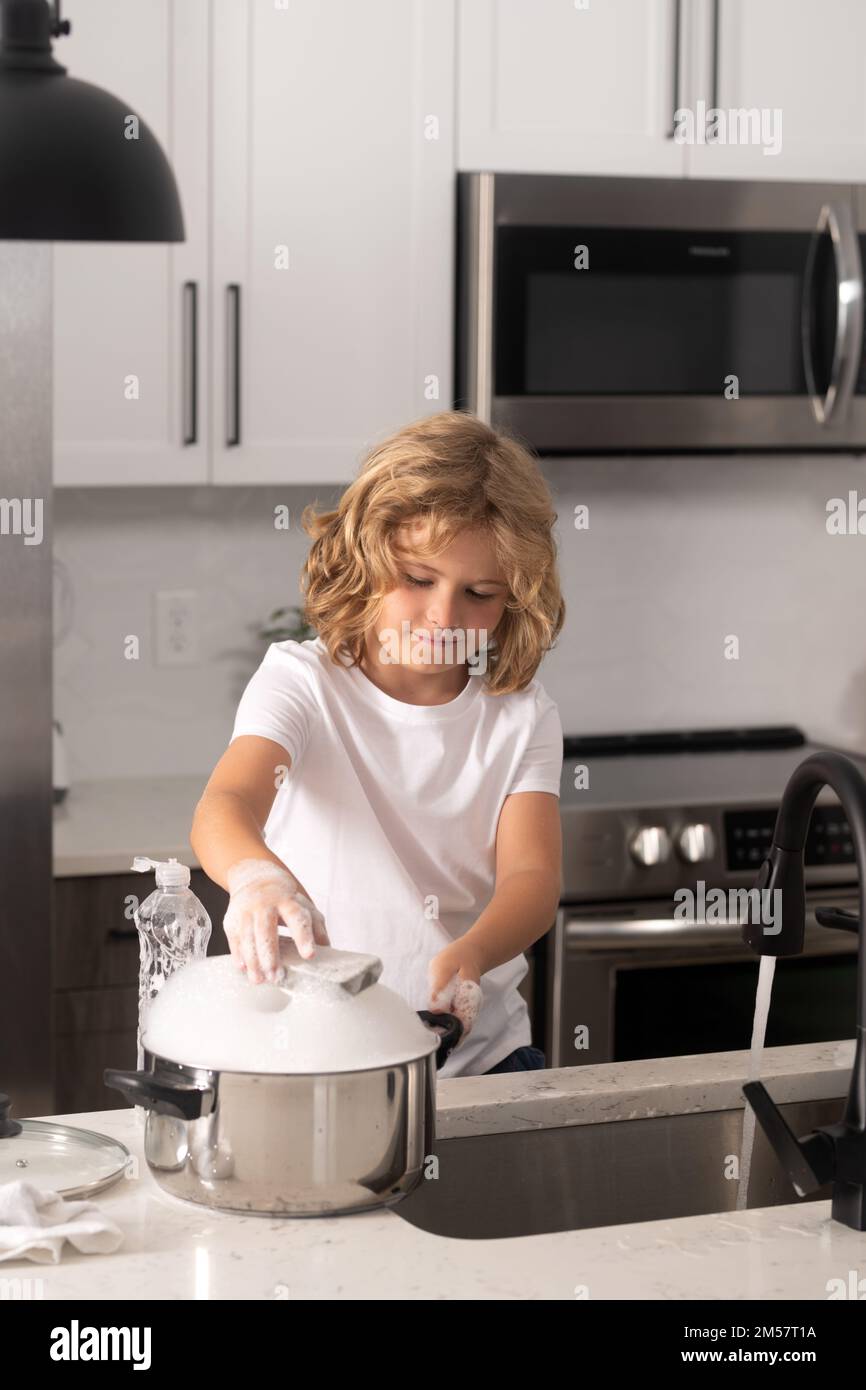 Child boy washing the dishes in the kitchen sink. Cleaning dishwashing ...
