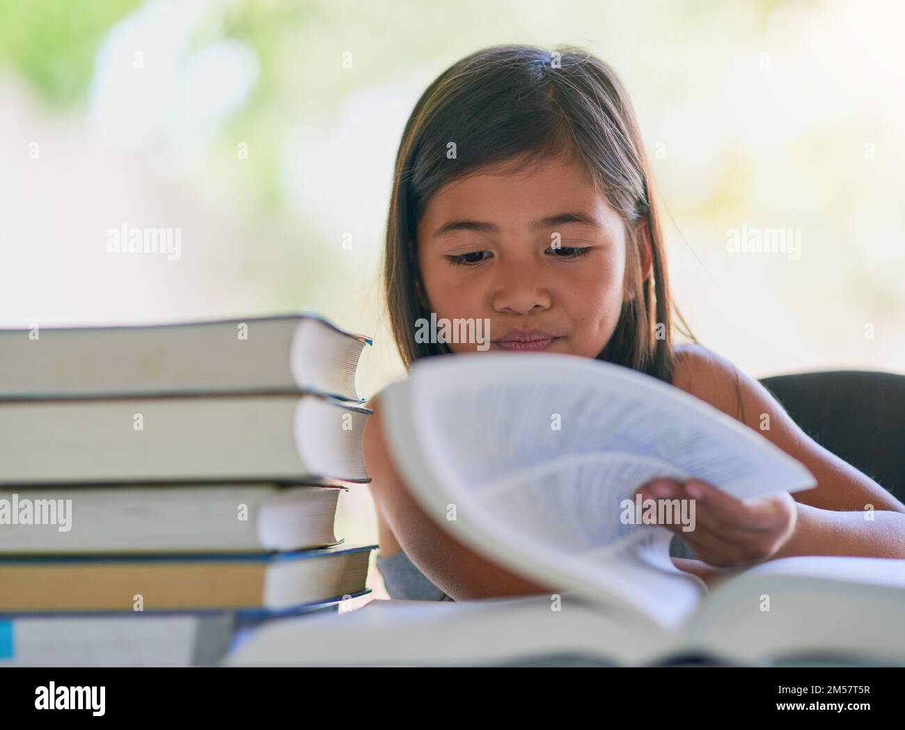 Shes a big bookworm. a little girl reading a book at home Stock Photo ...
