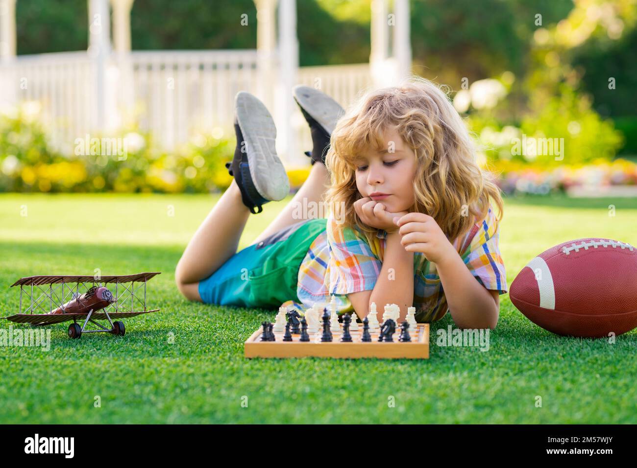 Early development. Boy thinking about chess in summer park. The concept ...