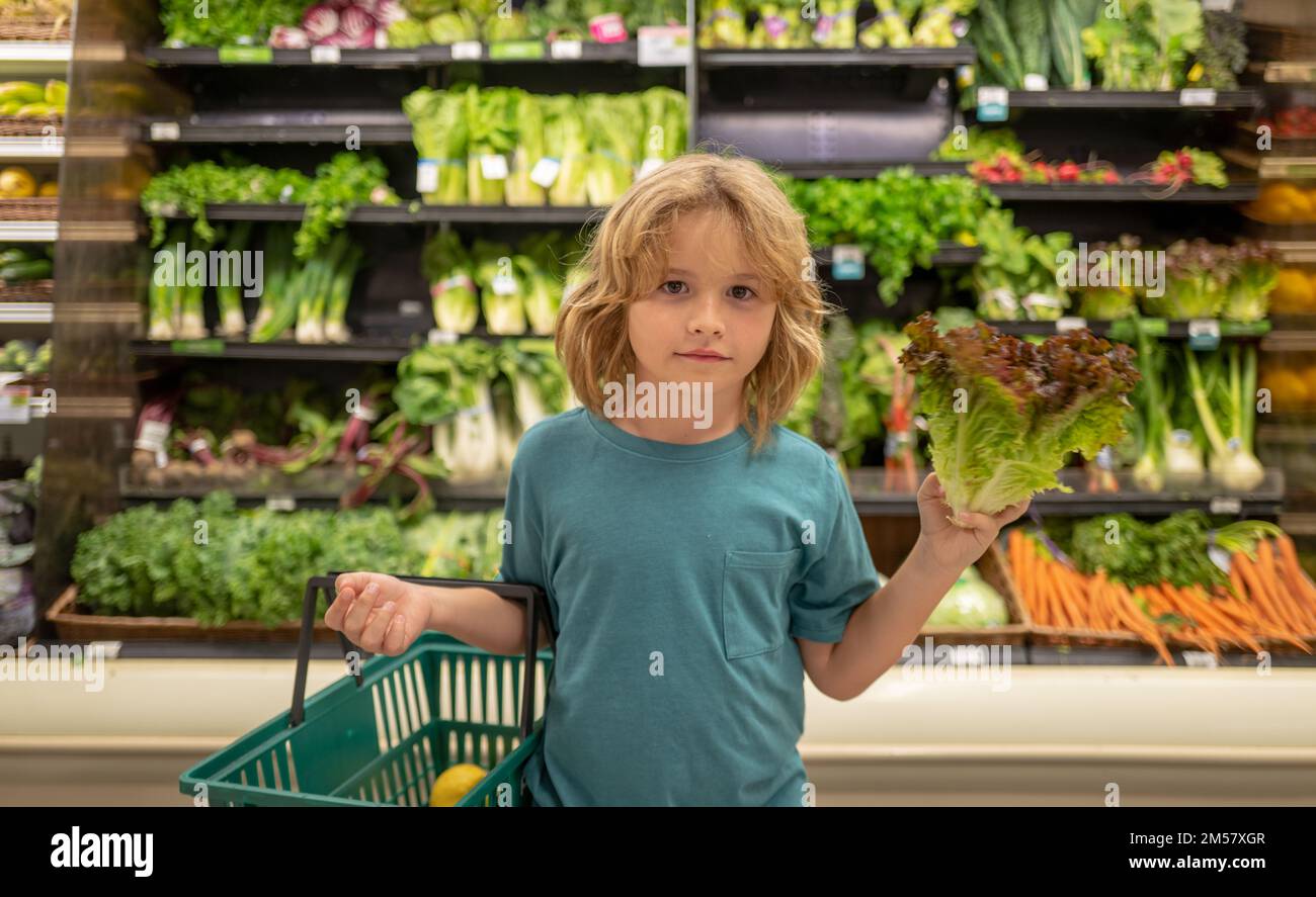 Child with lettuce salad. Kid in a food store or a supermarket. Little ...
