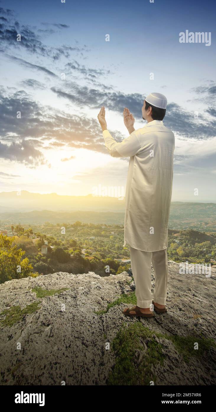 Muslim man standing while raised hands and praying on the hill Stock ...