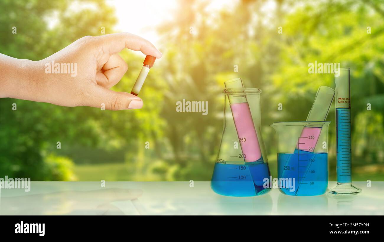 Human hand holding a test tube with colorful chemicals in laboratory ...