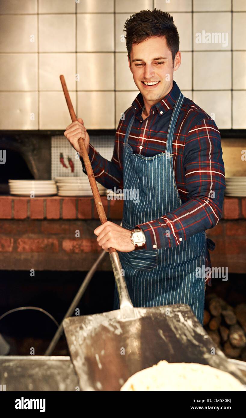 My pizza is what the customers come back for. a young man using a peel ...