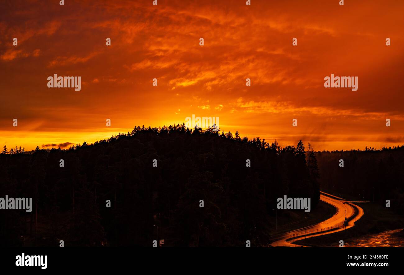 A breathtaking view of red cloudy sunset sky over silhouettes of ...