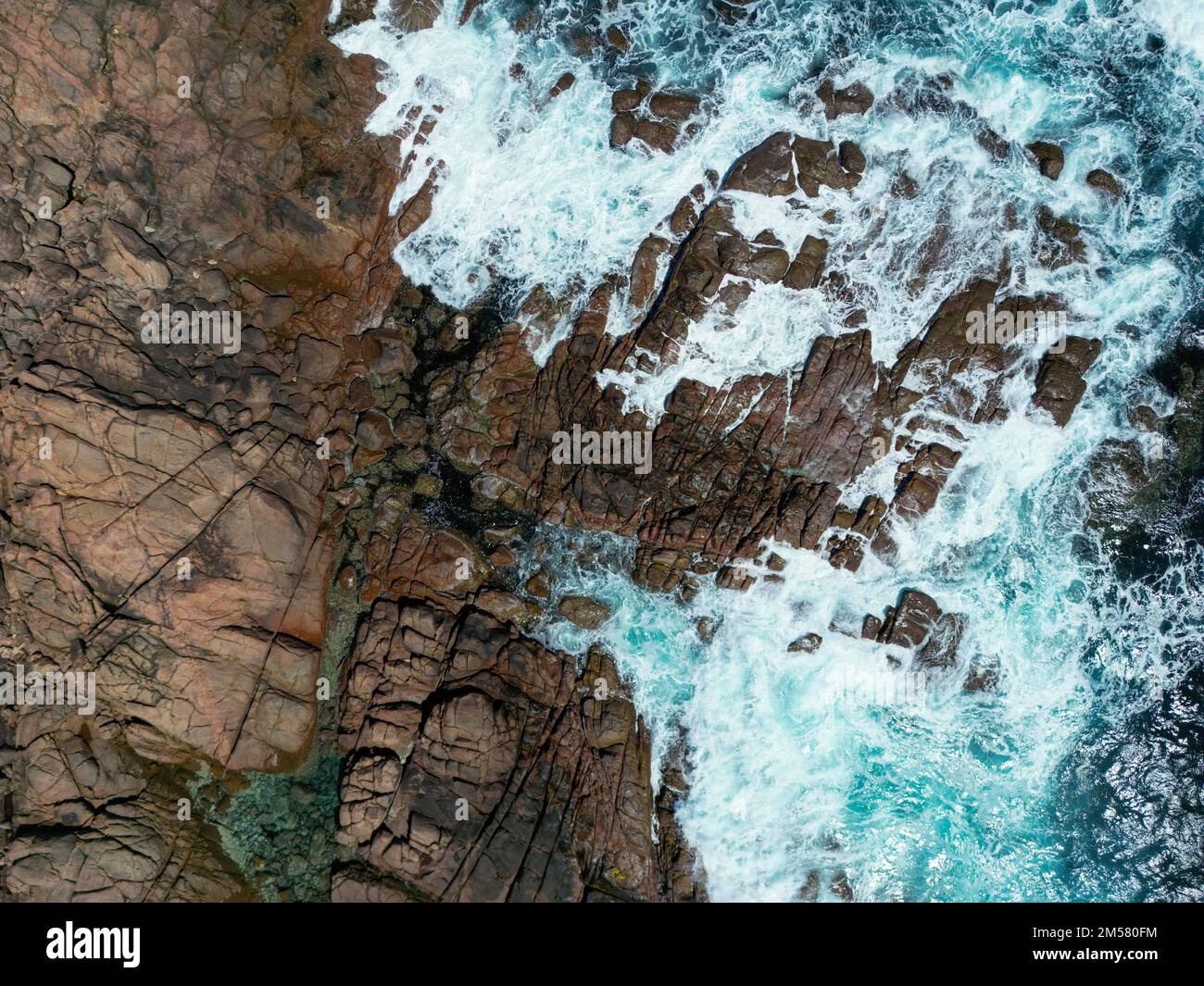 An aerial view of the coast with rocks and blue ocean waves in daylight ...