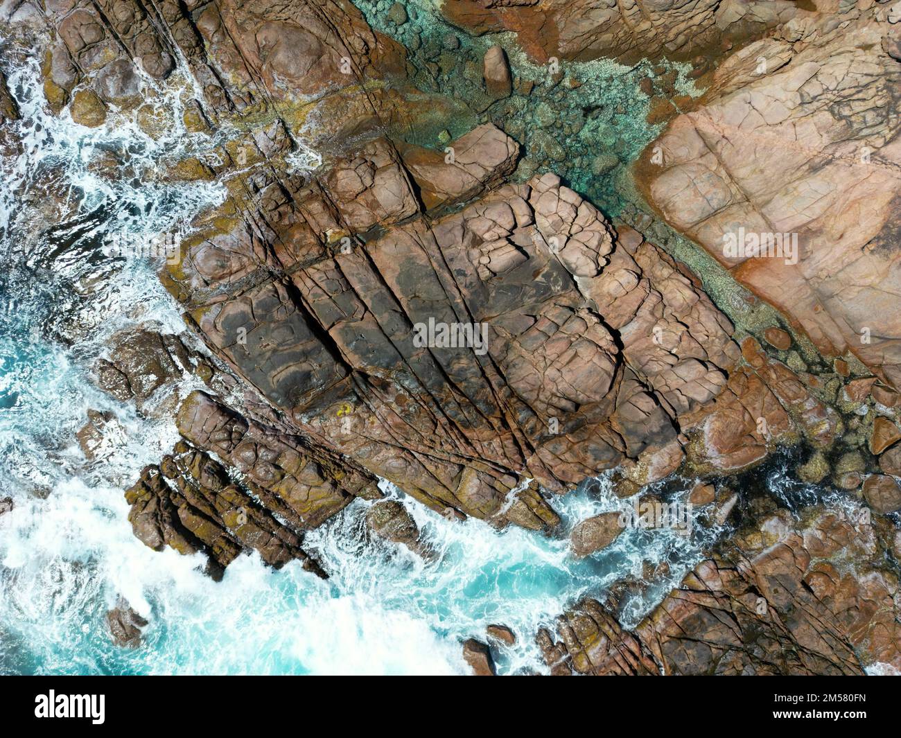 An aerial view of the coast with rocks and blue ocean waves in daylight ...