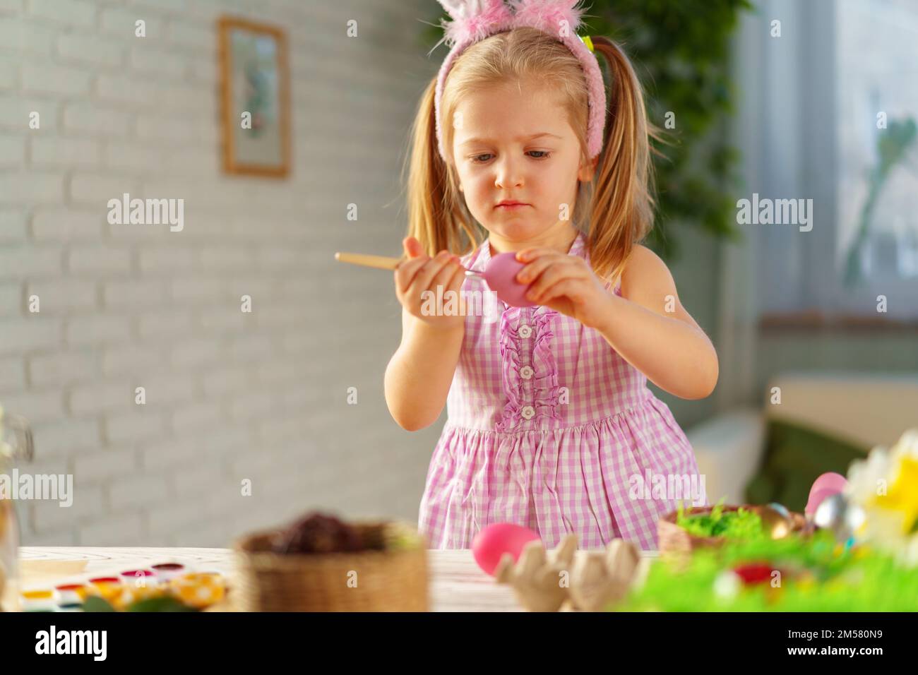 Toddler girl with bunny ears coloring eggs for Easter Stock Photo - Alamy