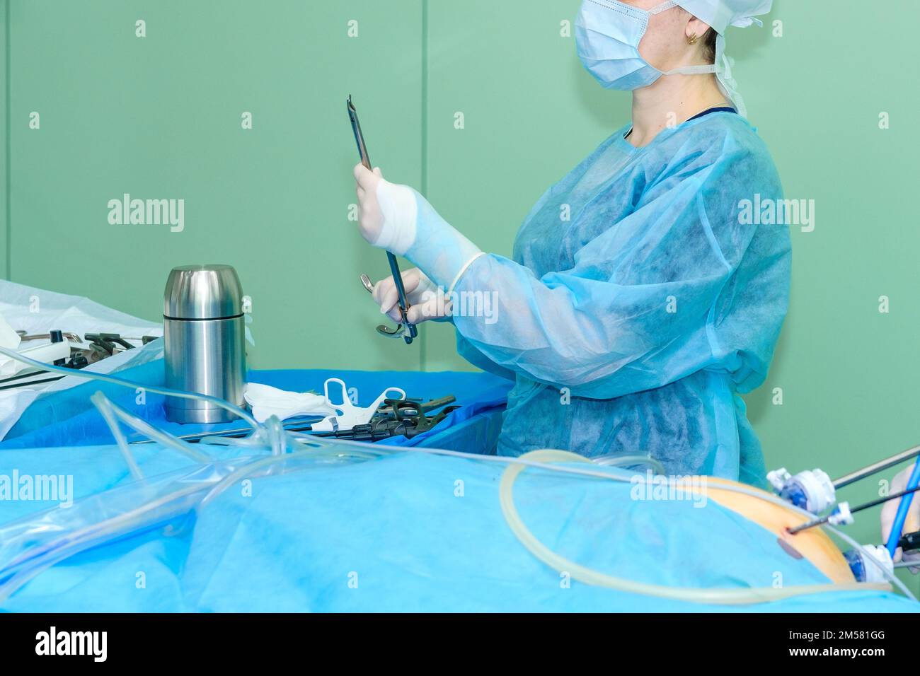 The doctor holds a sterile surgical instrument near the table in the ...