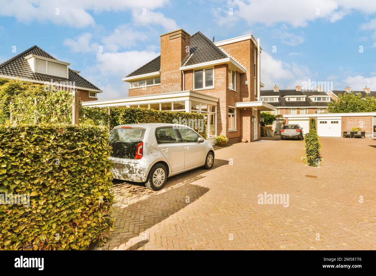 a house with a car parked in the driveway and two cars parked on either ...