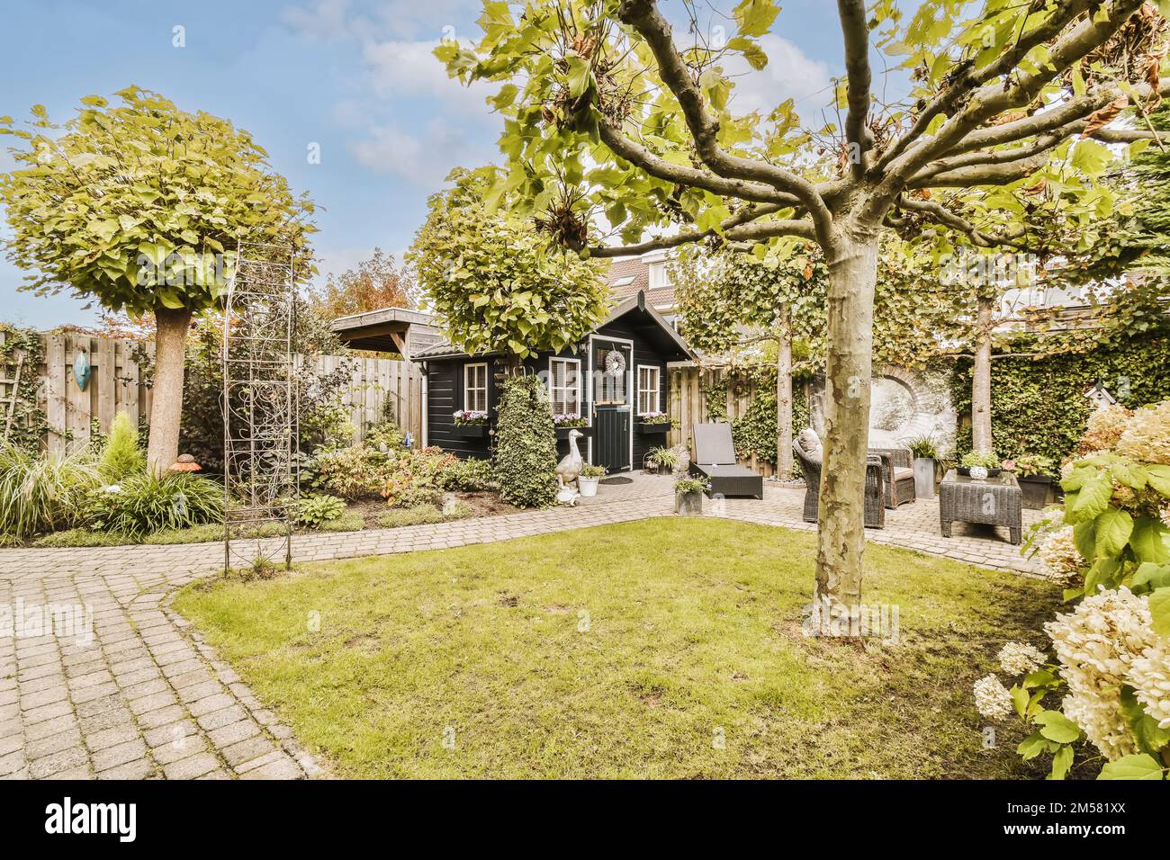 the back garden with trees and flowers in blooming, surrounded by lush ...