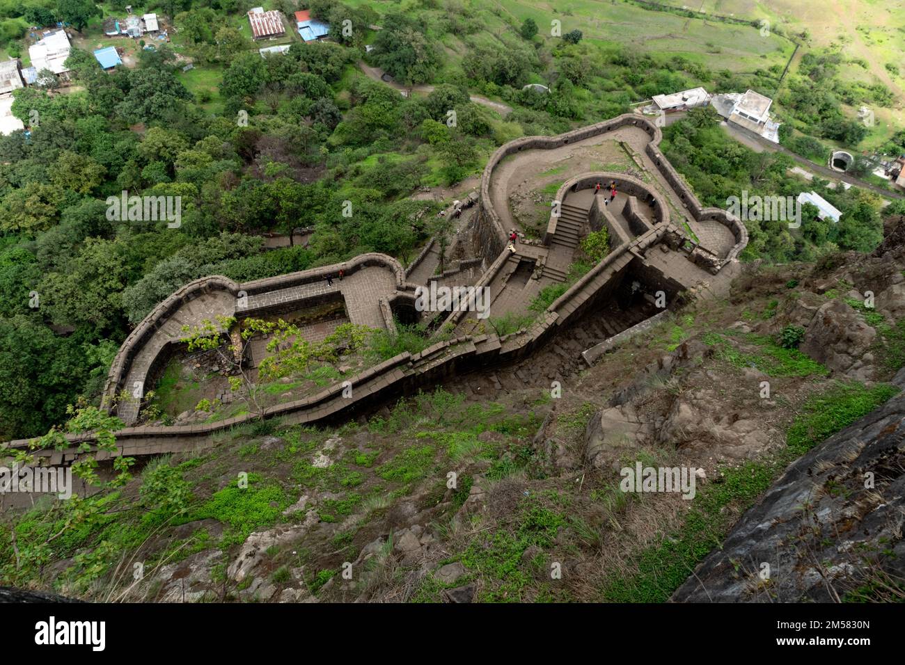 An aerial shot of Lohagad Fort surrounded by green trees and buildings ...