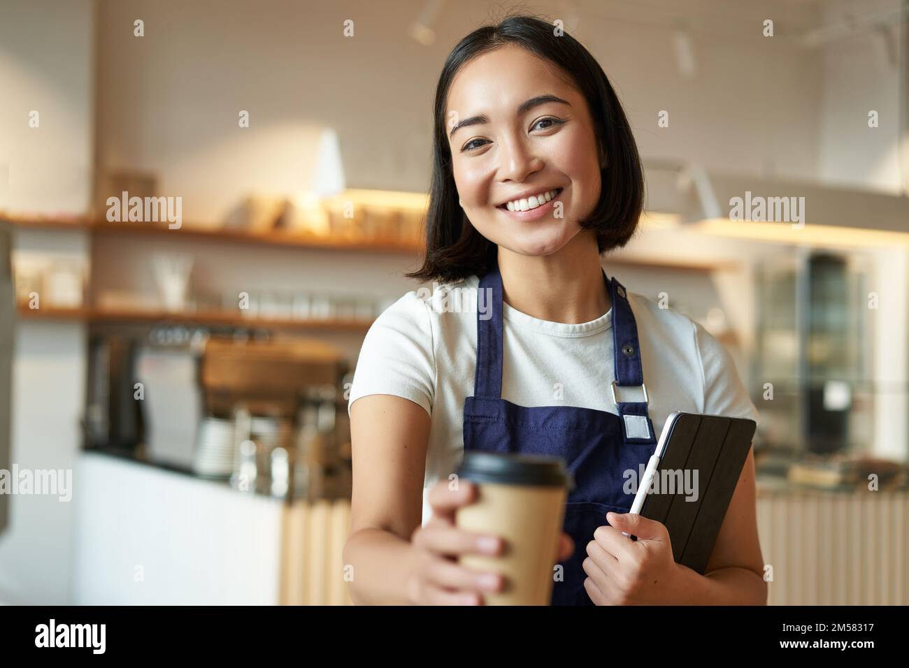 Smiling friendly waitress in coffee shop, barista giving out takeaway ...