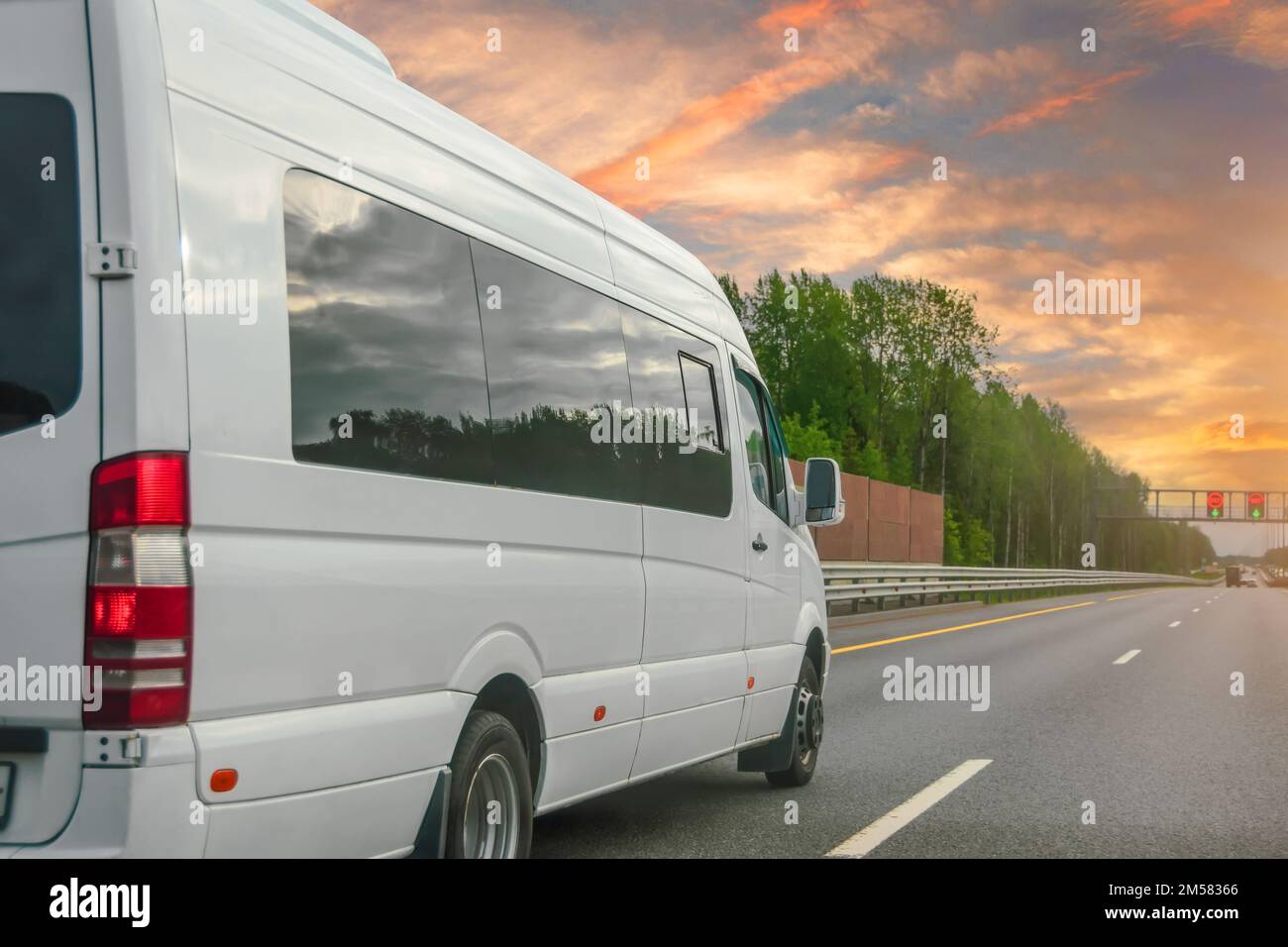 White modern passenger charter van with a small delivery moves fast on ...