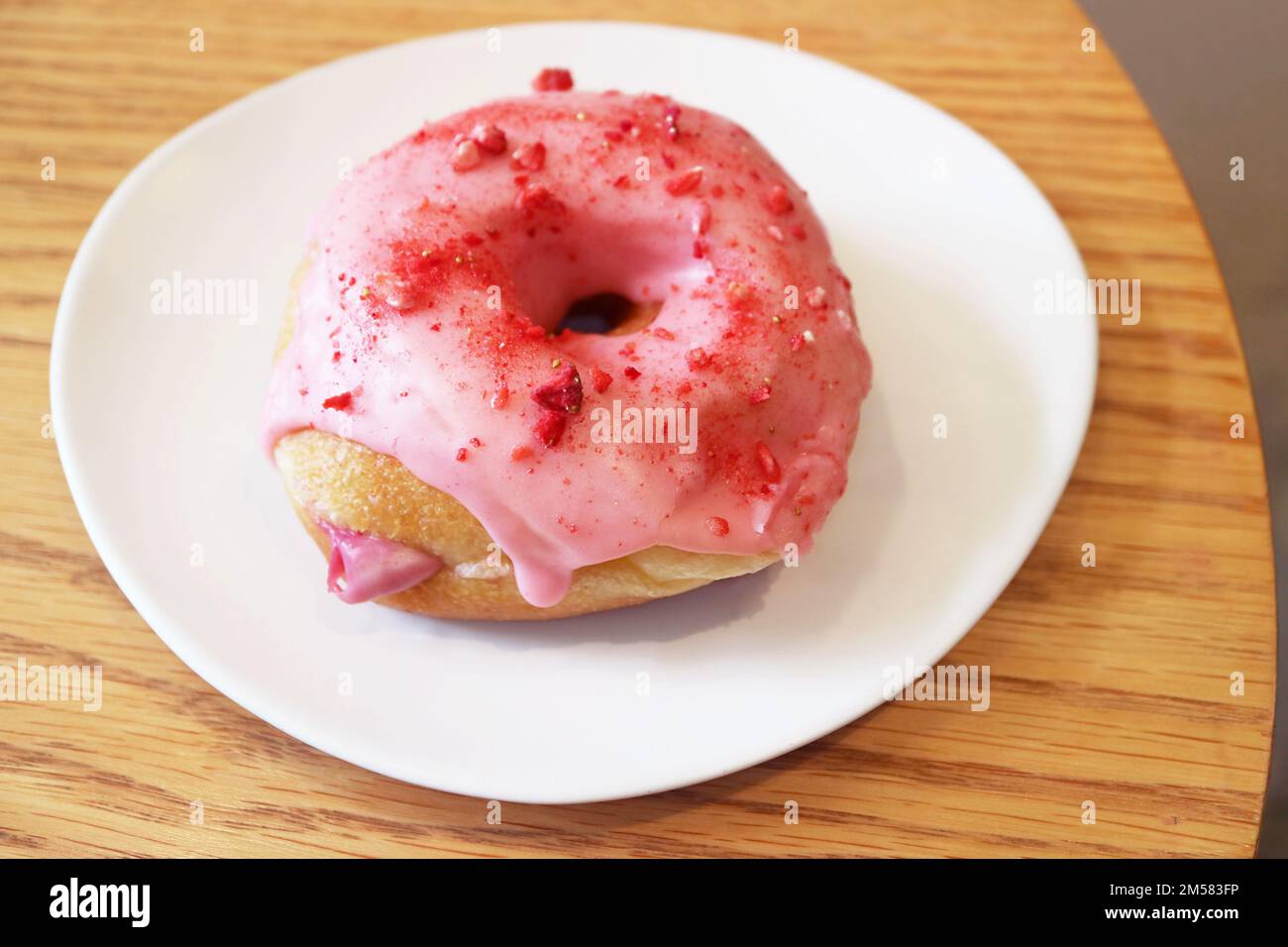 Delectable strawberry-glazed with raspberry cream filling doughnut on a ...
