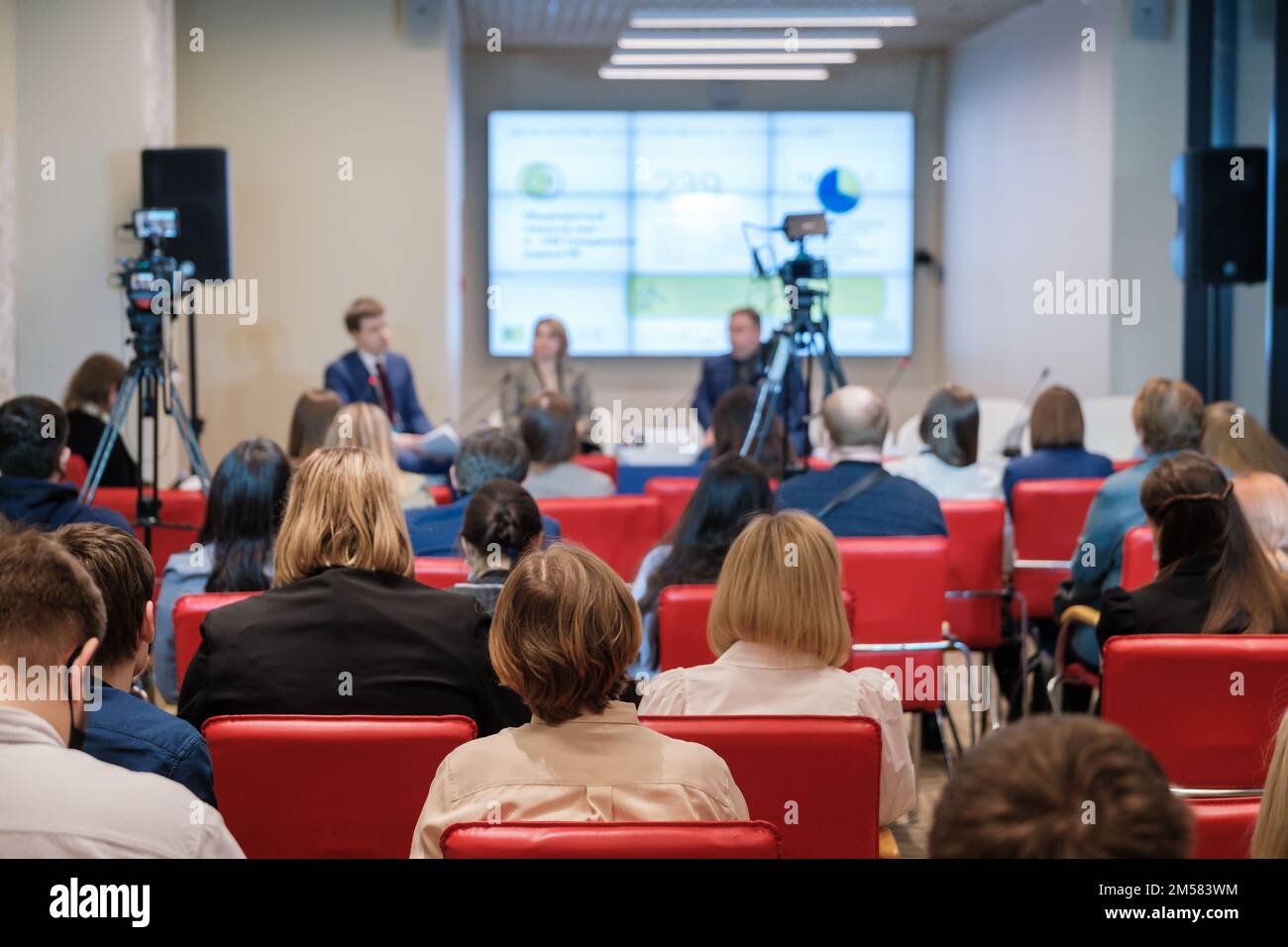Anonymous people sitting on chairs in modern hall and listening to ...