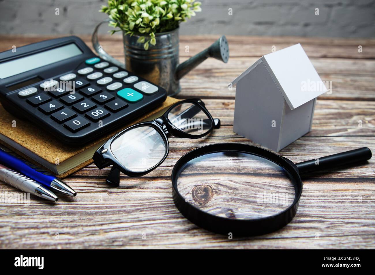 White Model House with magnifying glass and calculator on wooden ...