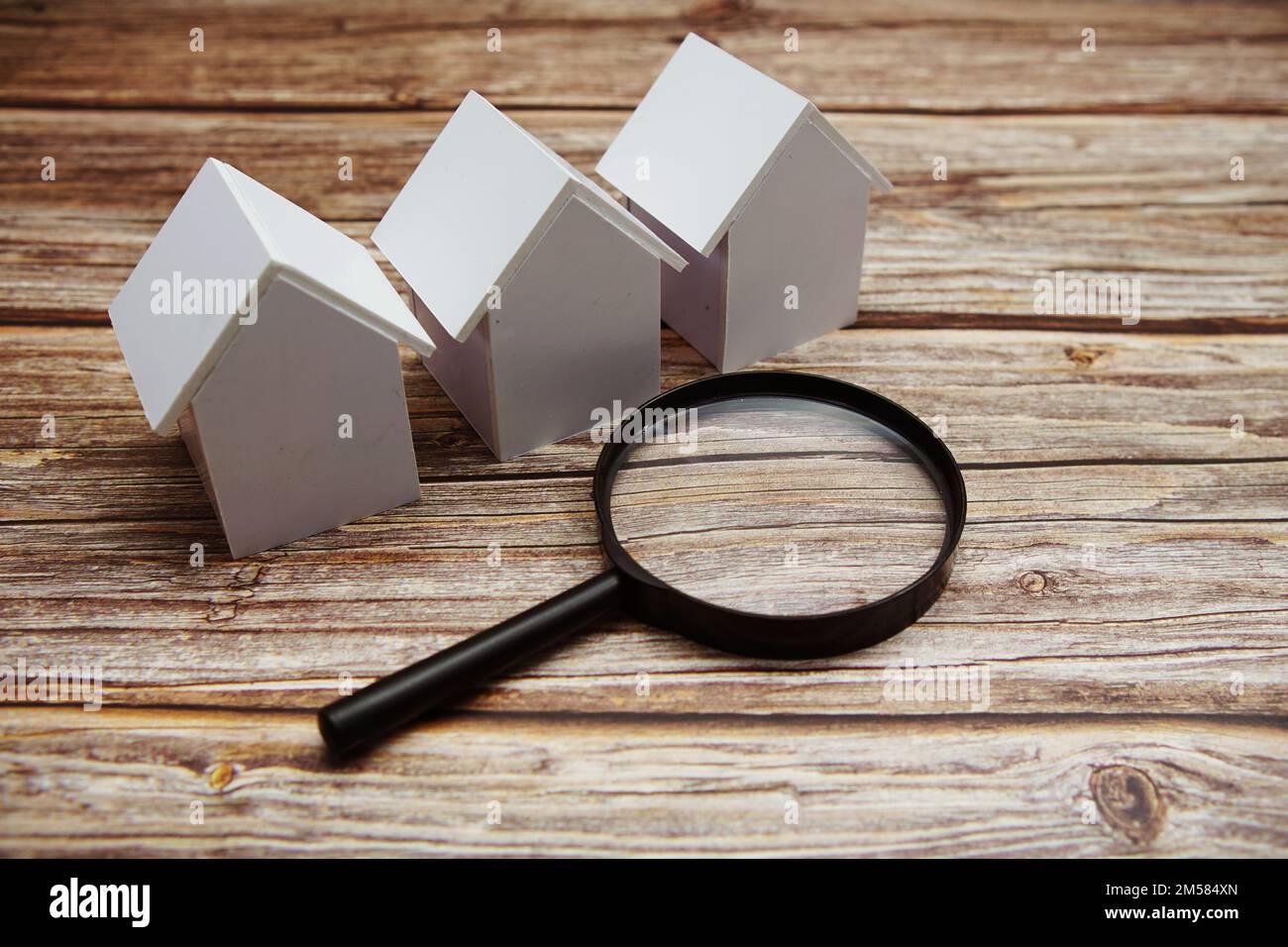 Model House and magnifying glass on wooden background Stock Photo - Alamy