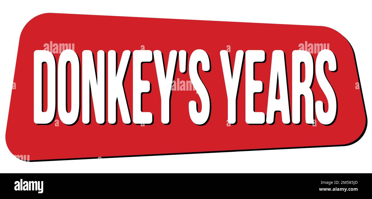 DONKEY'S YEARS text written on red trapeze stamp sign Stock Photo - Alamy