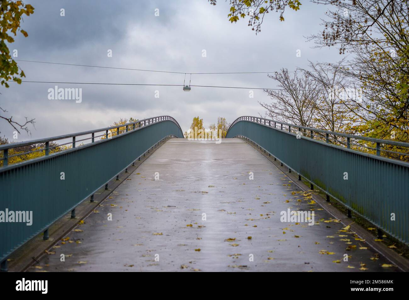 A steep pedestrian bridge leads towards the sky with a light hanging on ...