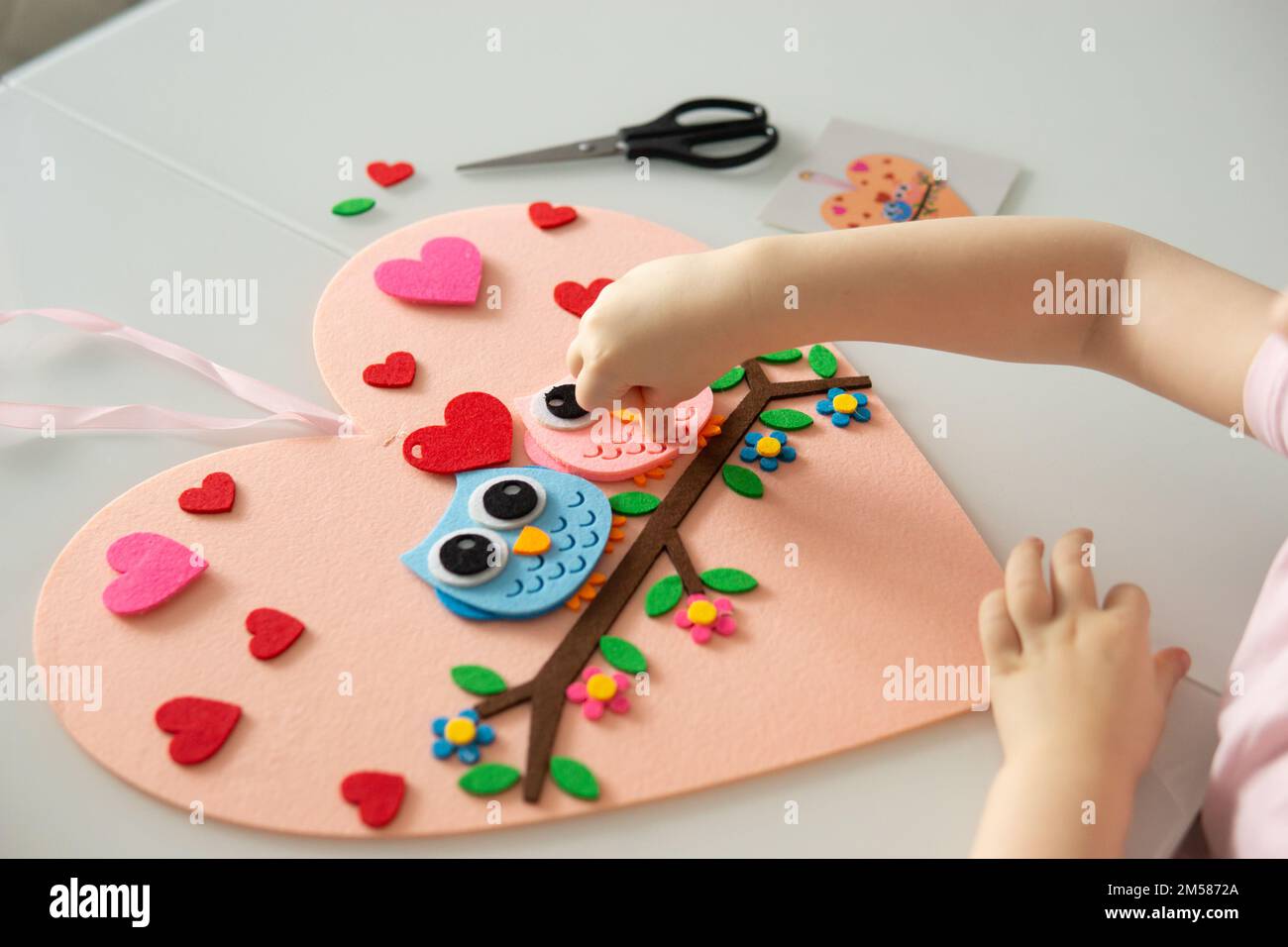 A blogger girl makes a felt craft for Valentine's Day in the shape of a ...