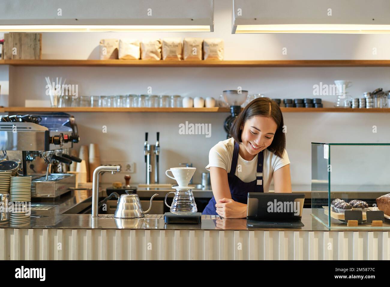 Happy smiling asian barista, girl behind counter, working with POS ...