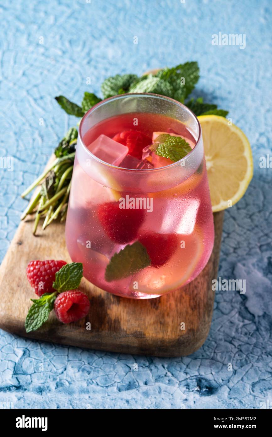 Raspberry lemonade drink in glass on blue background Stock Photo - Alamy